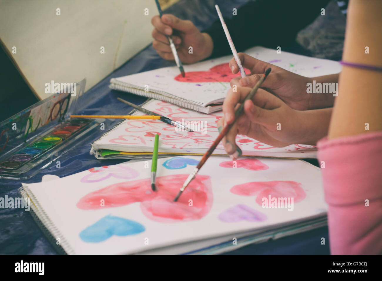 Photograph of some hands with paintbrushes painting hearts Stock Photo ...