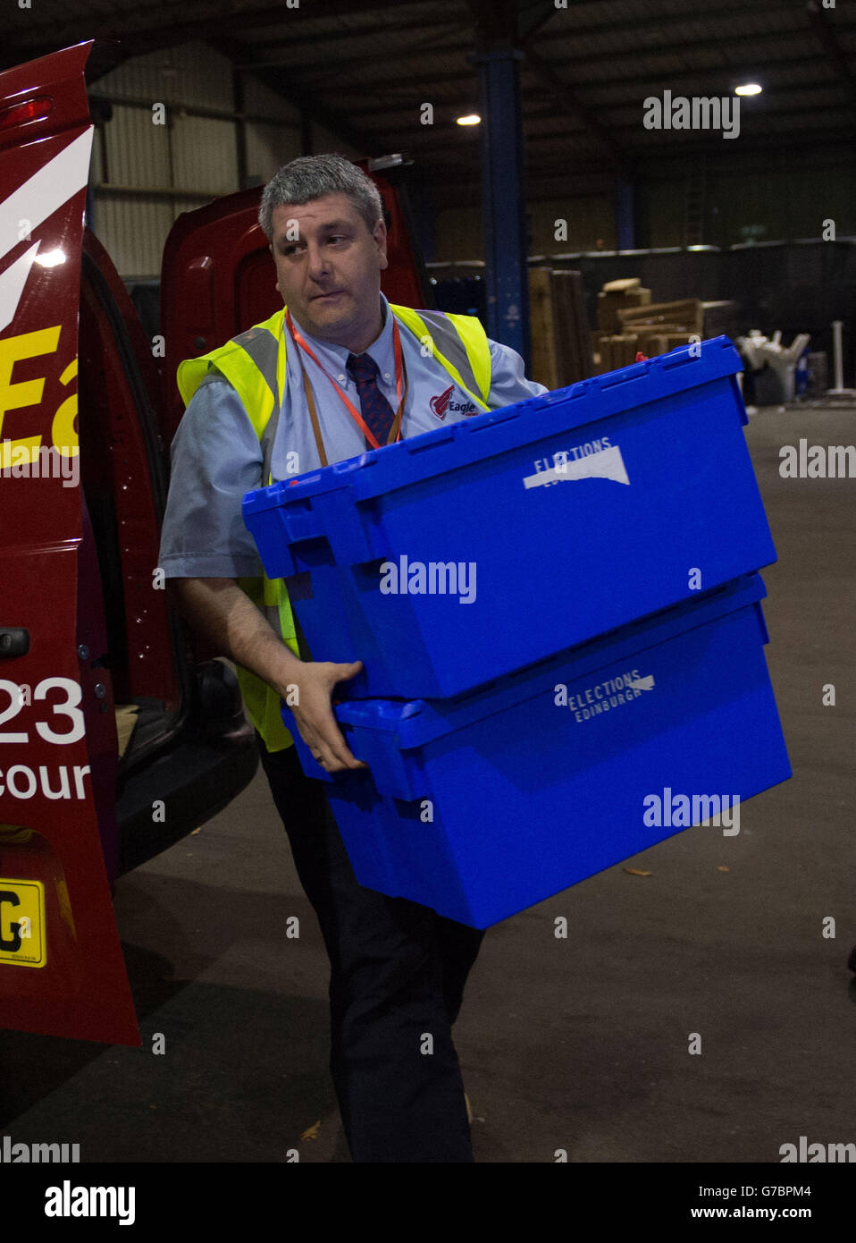 A volunteer carries the first boxes of polling station ballots returned ...