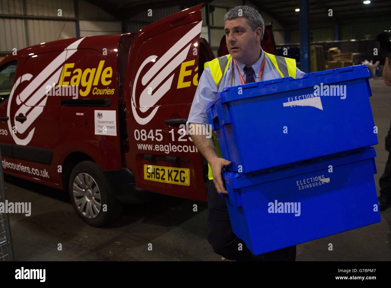 A volunteer carries the first boxes of polling station ballots returned ...