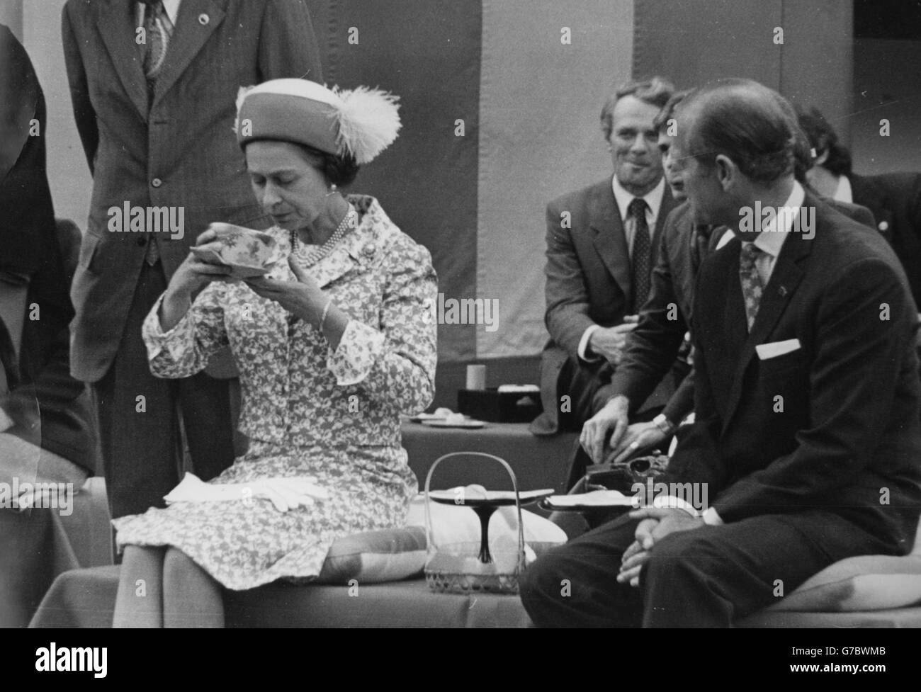 Queen Elizabeth II sips a cup of tea during a ceremony in a garden at ...