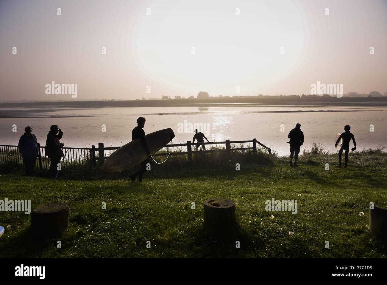Surfers make their way down the grass banking to enter the River Severn ...
