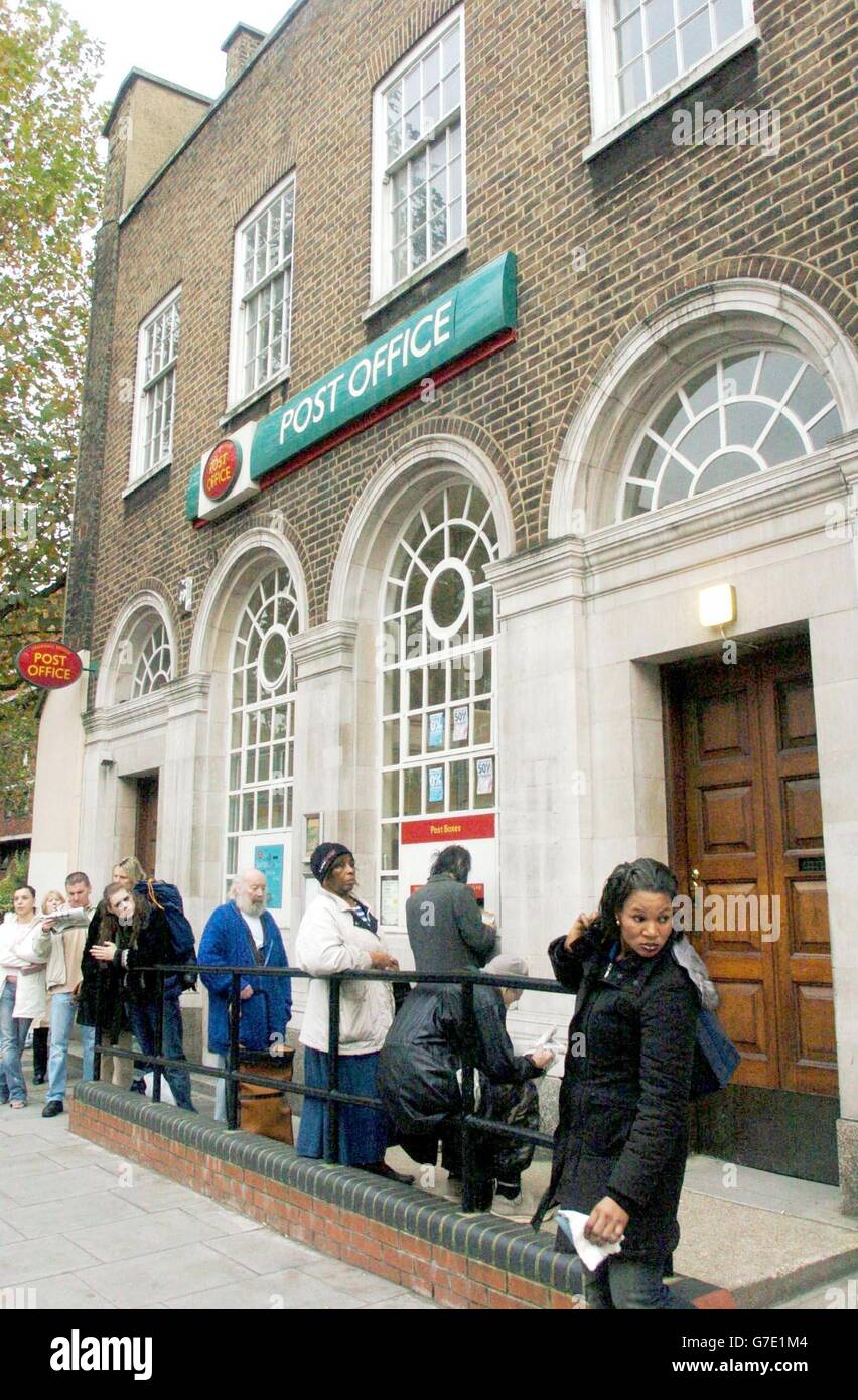 A queue of people builds up before opening-time outside a post office ...