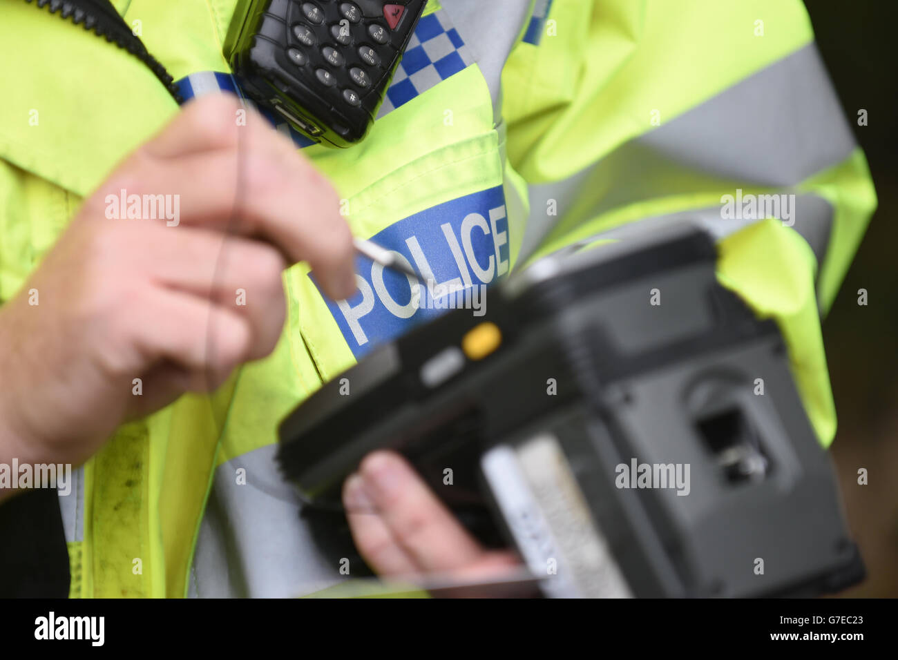 A police officer checks a drivers details on a mobile identification ...