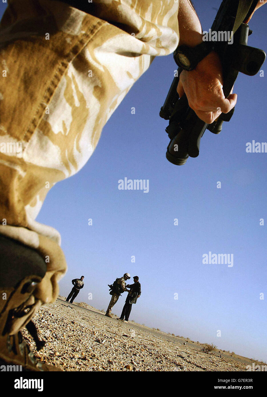 A British soldier attached to the Black Watch searches Iraqi men at a ...