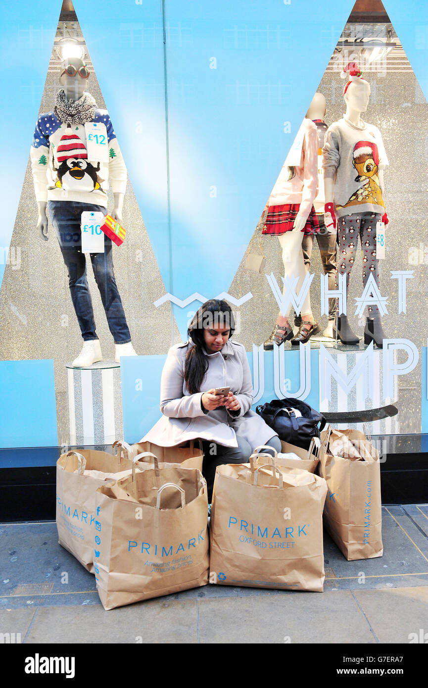 A woman, surrounded by Primark bags, sits on the window ledge of ...