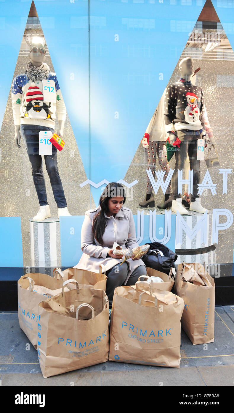A woman, surrounded by Primark bags, sits on the window ledge of ...