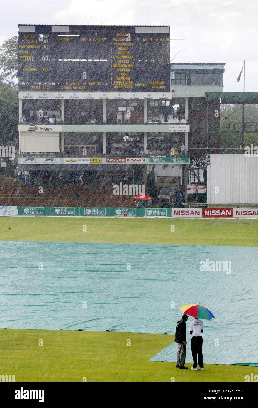 Ground staff cover the pitch as heavy rain sweeps down during the third ...