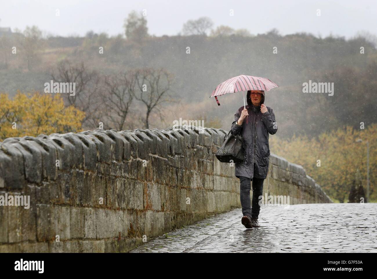 A woman walking with an umbrella in Stirling as Scotland continues to ...