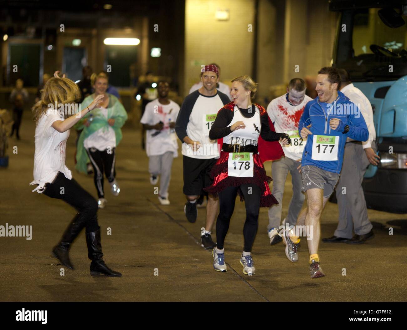People dressed as zombies chase participants during a zombie fun run at ...