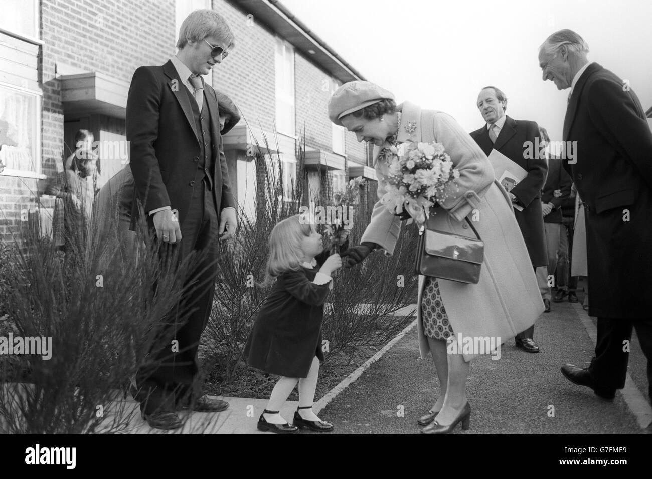 Queen Elizabeth II is presented with flowers by three-year-old Melanie ...