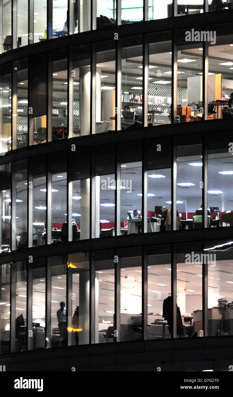 General view of office workers in the windows of an office block along ...