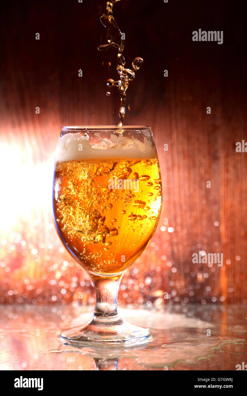 Beer flowing to glass with drops on dark background Stock Photo - Alamy