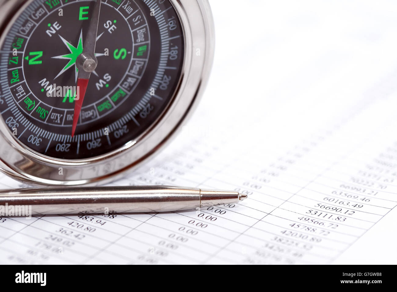 Business direction. Closeup of compass near pen on paper with digits ...