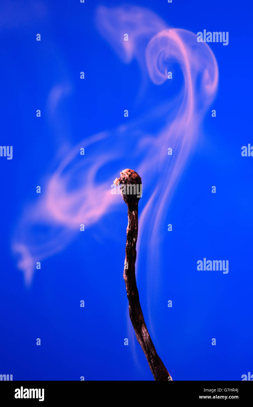Extinguished match with smoke on blue background Stock Photo - Alamy