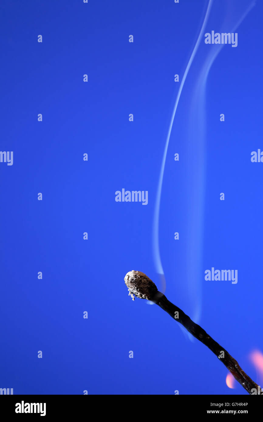 Extinguished match with smoke on blue background Stock Photo - Alamy
