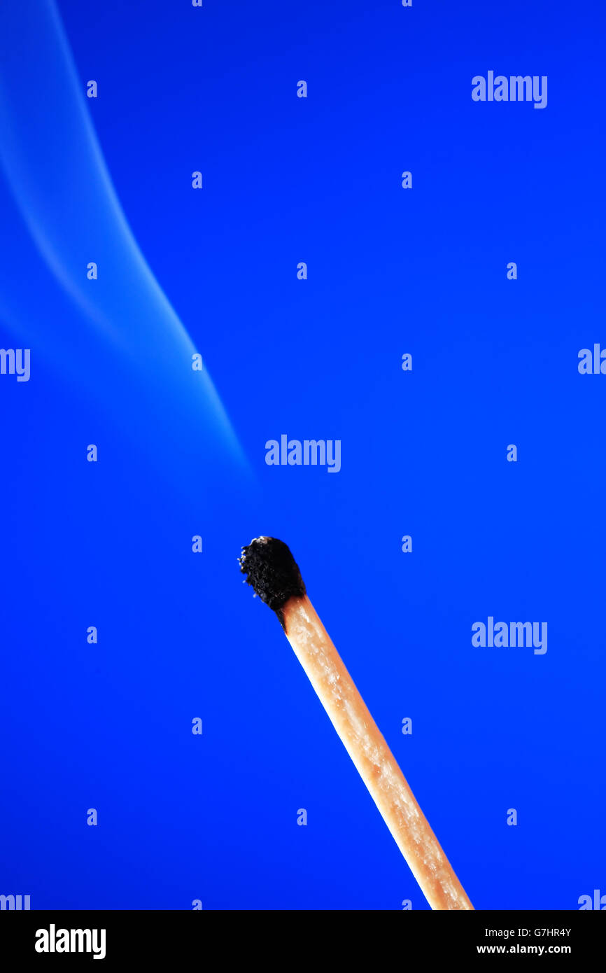 Extinguished match with smoke on blue background Stock Photo - Alamy