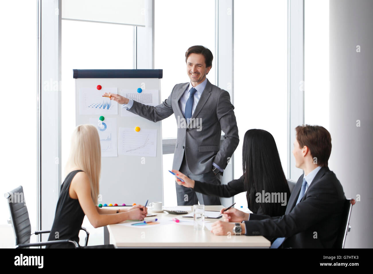 Workers at business meeting looking at presentation of financial ...