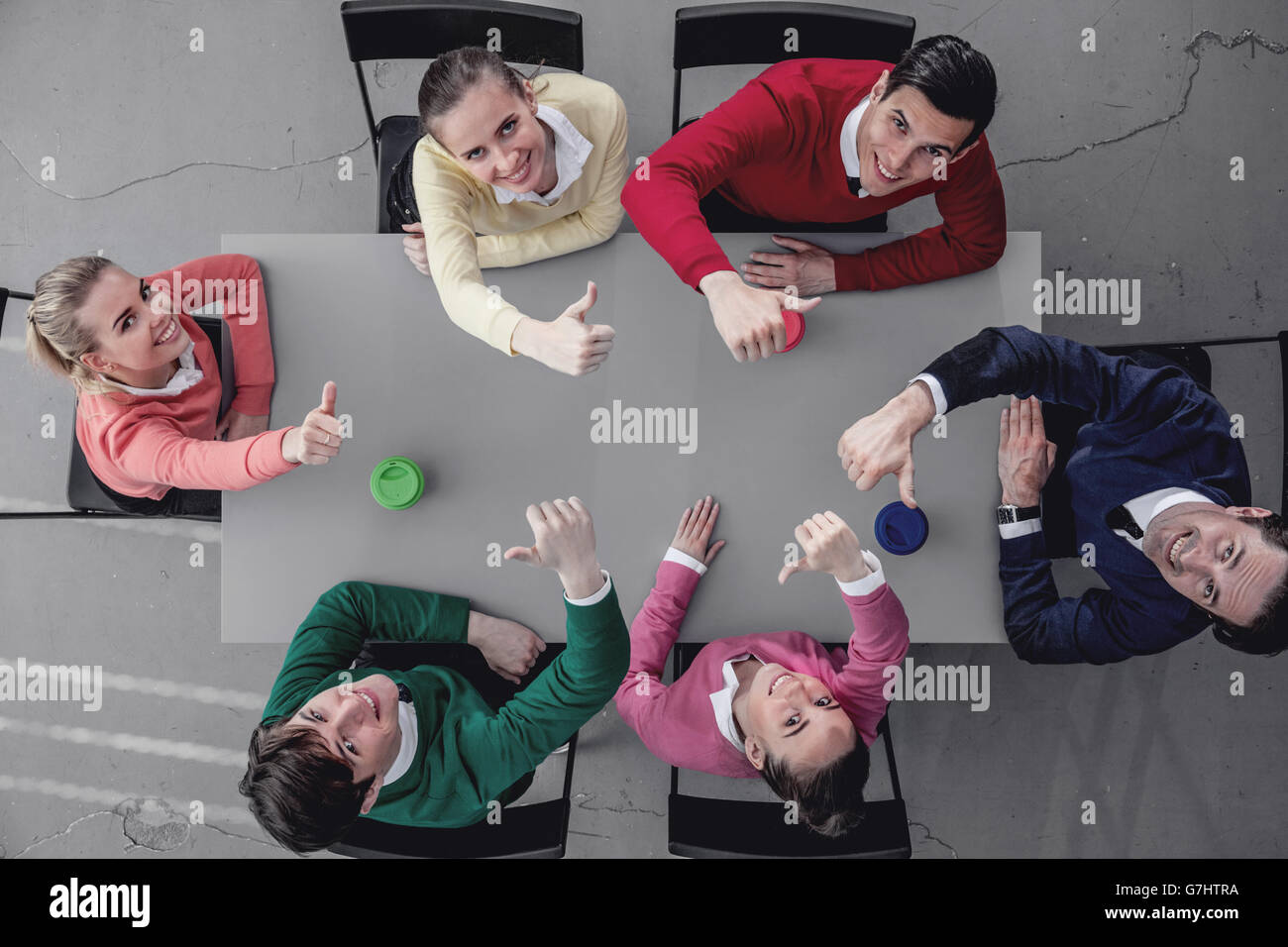 Team of happy workers around the table with thumbs up Stock Photo - Alamy