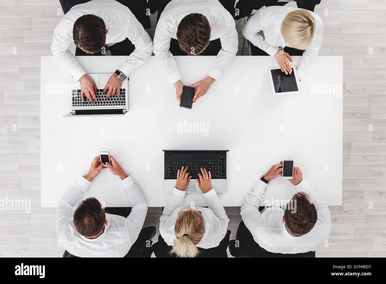 Business people sitting around the table with diverse electronic ...