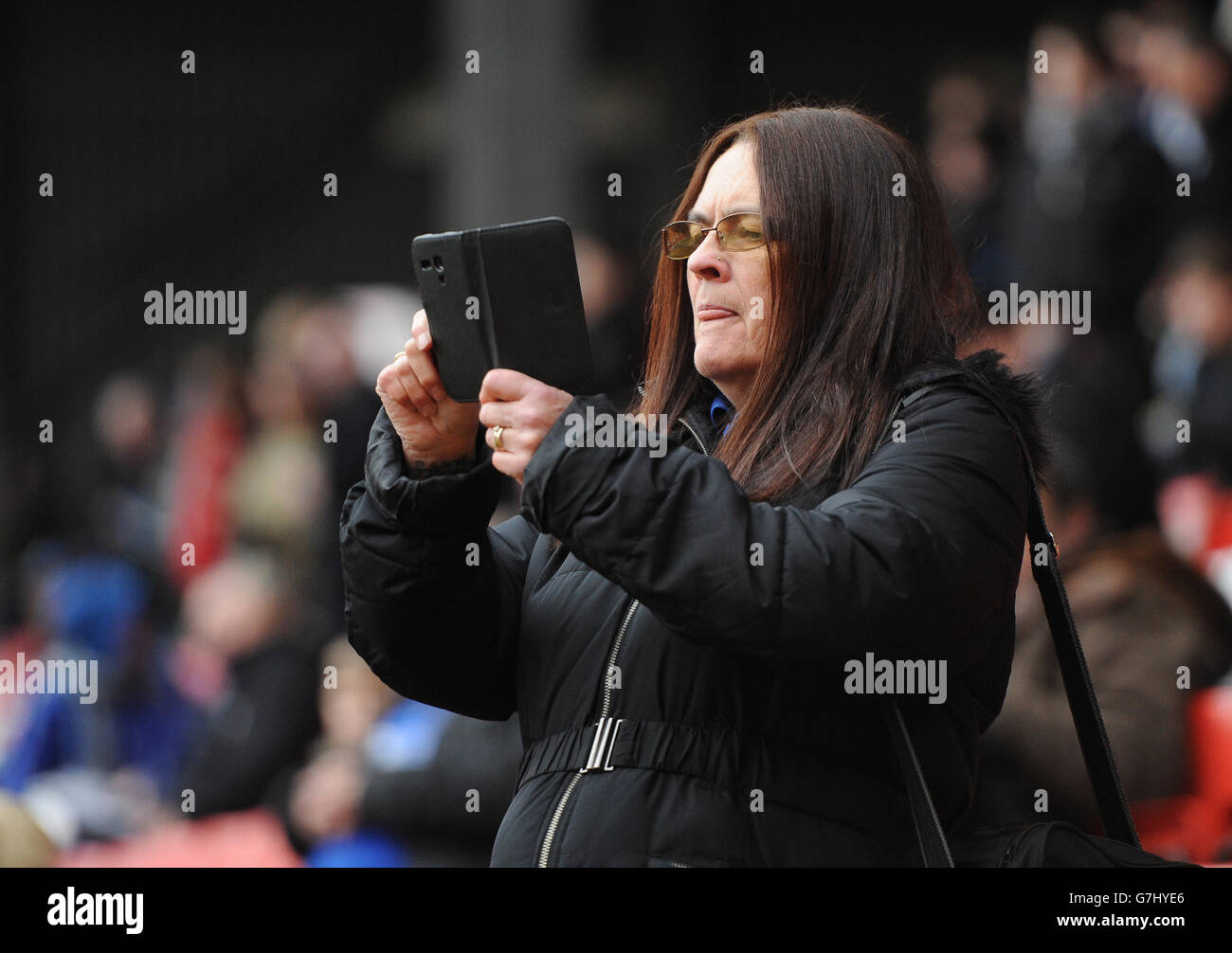A Cardiff City fan takes pictures with her smart phone in the stands ...