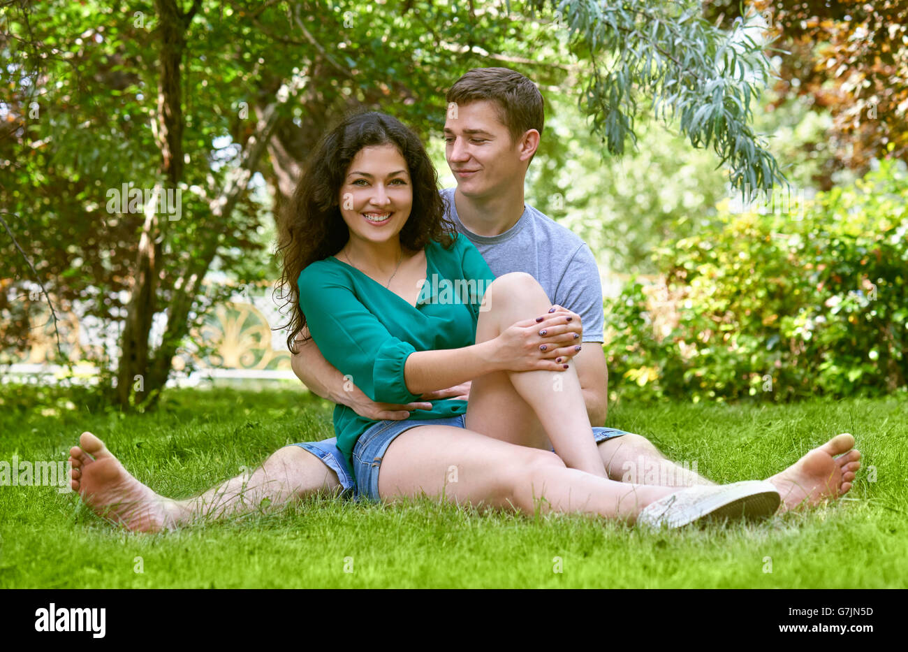 Romantic couple sit on grass in city park, summer season, lovers boy ...