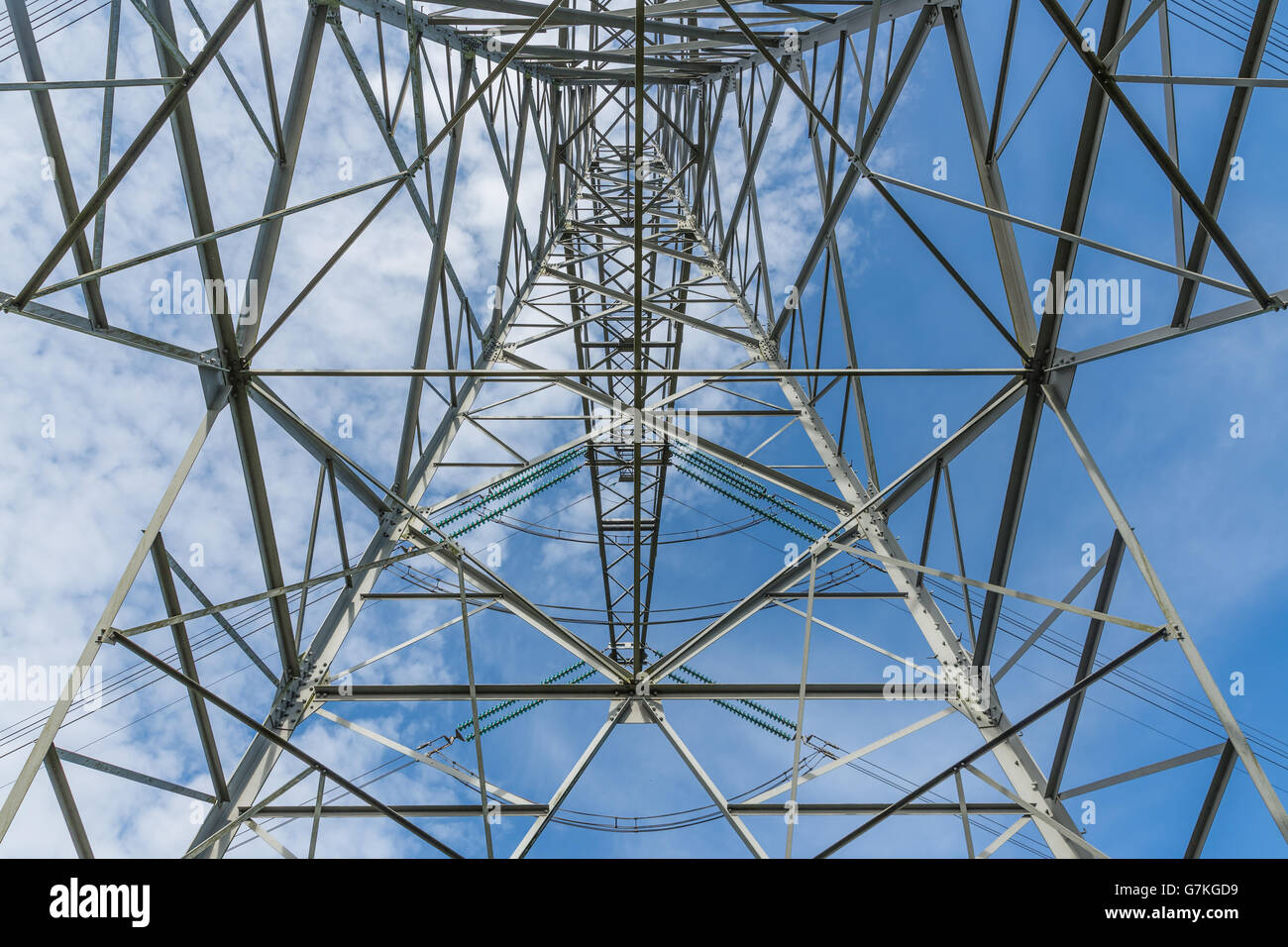 Symmetrically bottom view of electricity pylon against a blue sky ...