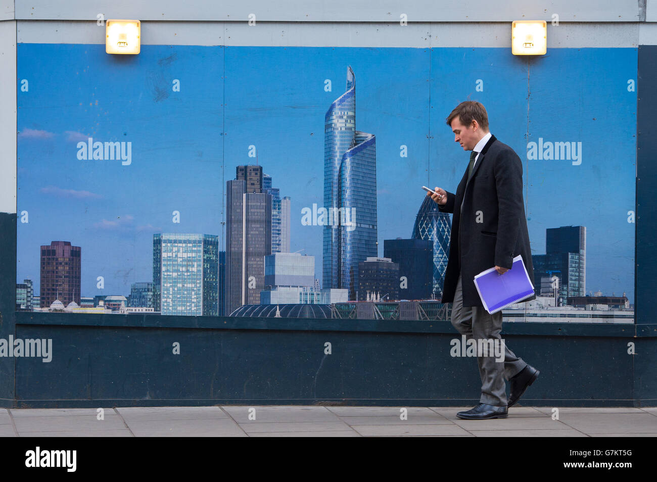 A man passes a billboard showing the London skyline in the City ...