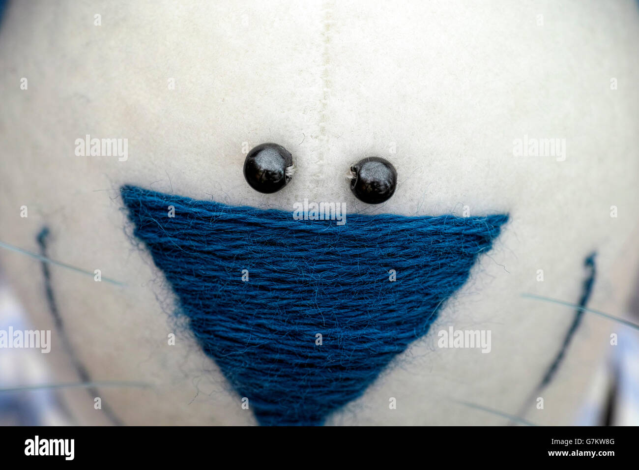 Closeup of toy face with blue embroidered nose and black bead eyes ...