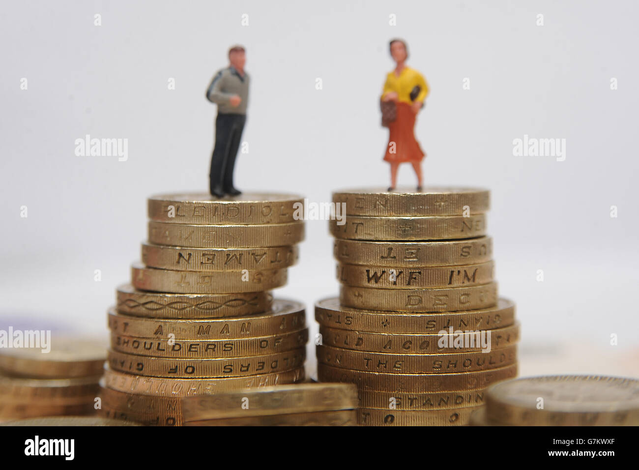 Plastic models of a man and woman stand on a pile of coins Stock Photo ...