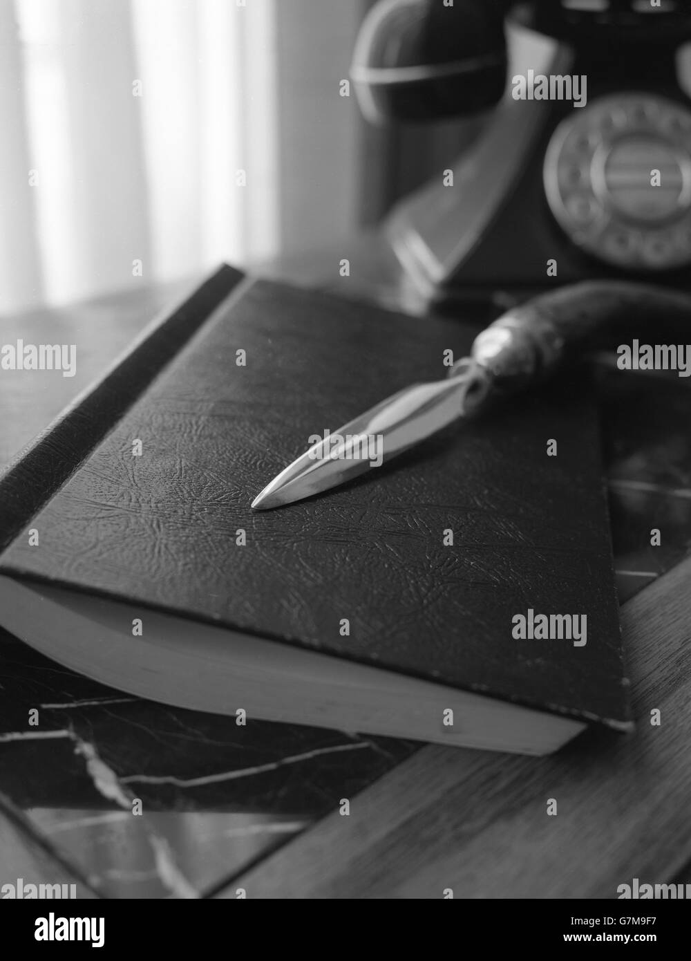 Letter opener on the back of an open book. Rotary style telephone ...