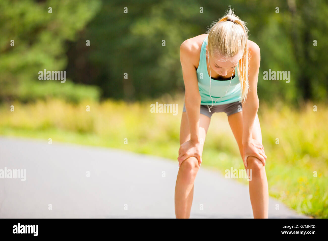 Woman leaning on knees and catch breath after stamina workout Stock ...