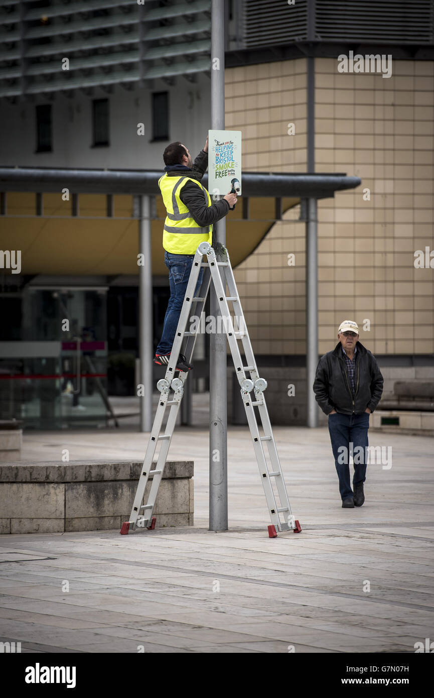 A man fixes a sign to a lamp post in Millennium Square in Bristol, as ...