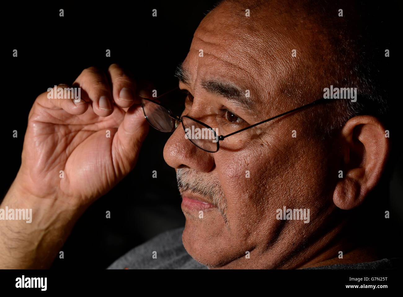 An older man wearing glasses and gazing into distance as if in deep ...