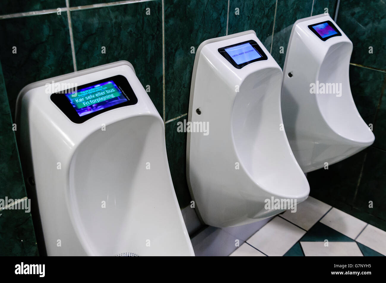 Urinals in a gents' toilet with LCD screens showing advertisements ...