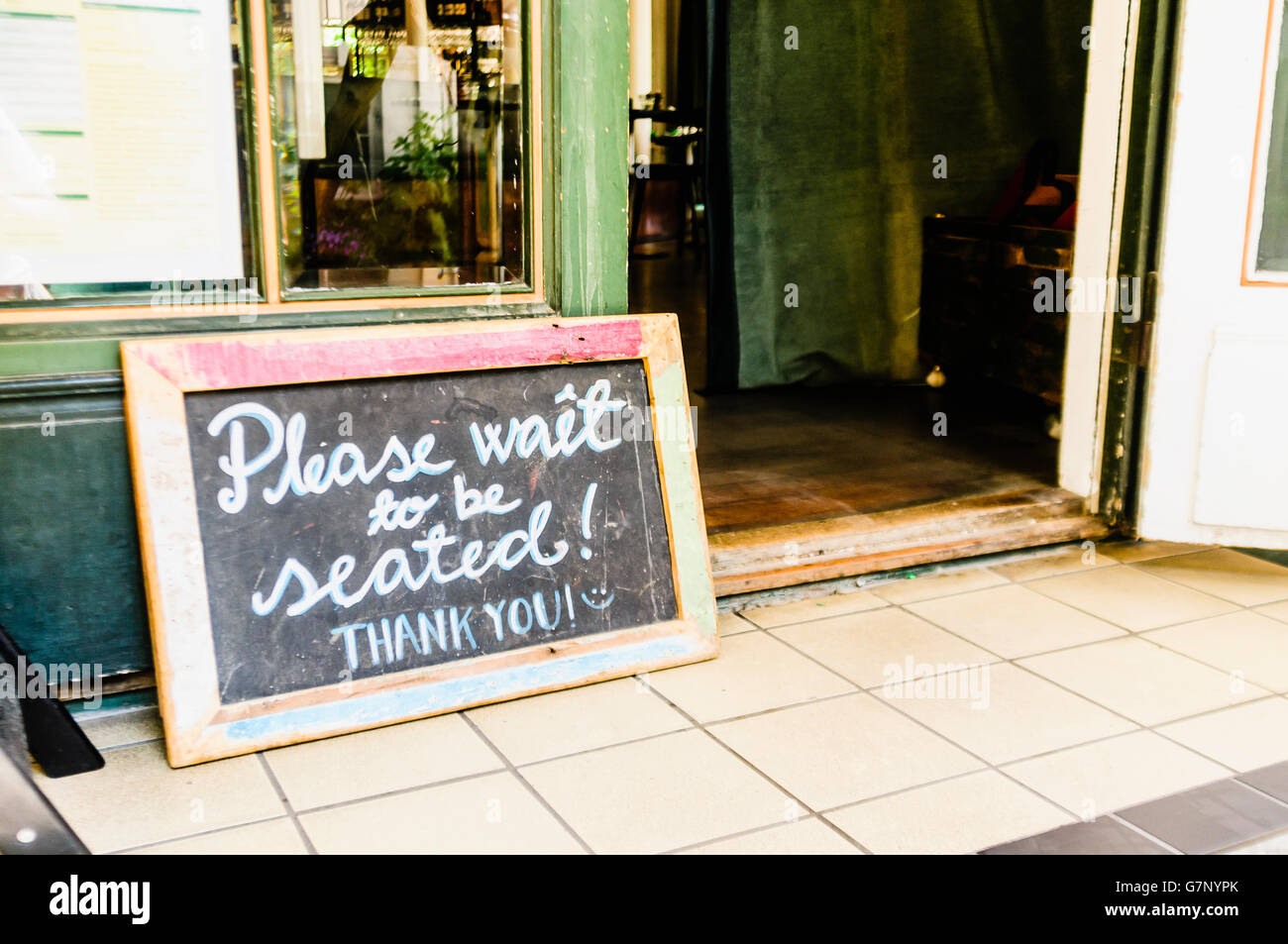 Sign outside a restaurant saying "Please wait to be seated! Thank you ...
