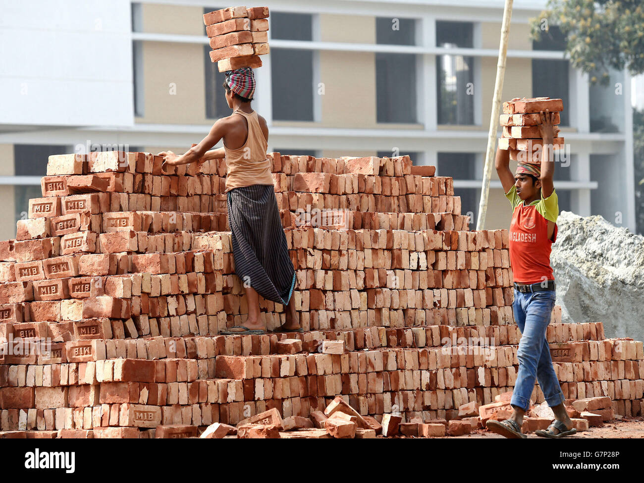 Young men carry bricks on the heads as they help to build a new ...