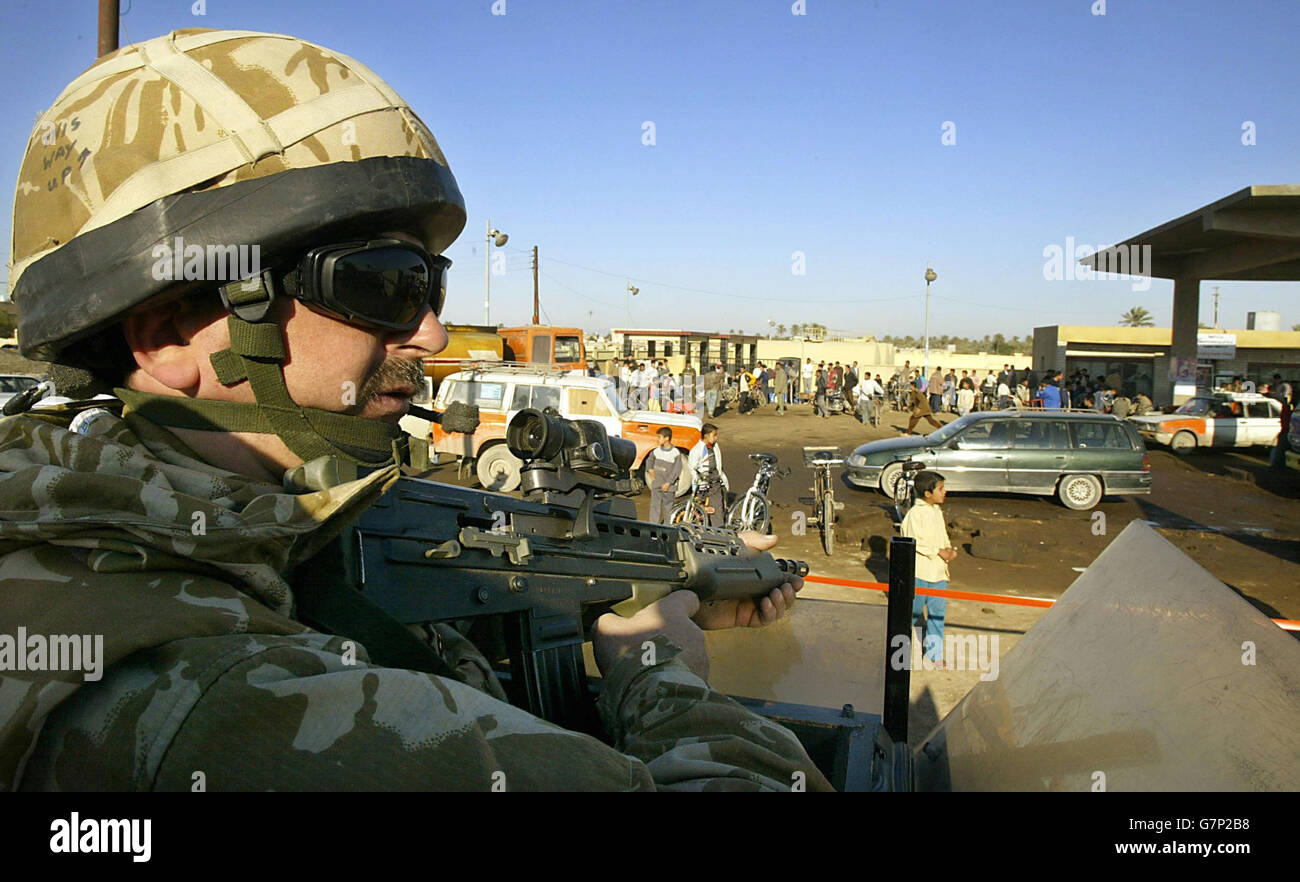 A British soldier from Div HQ watches a line of people waiting to get ...