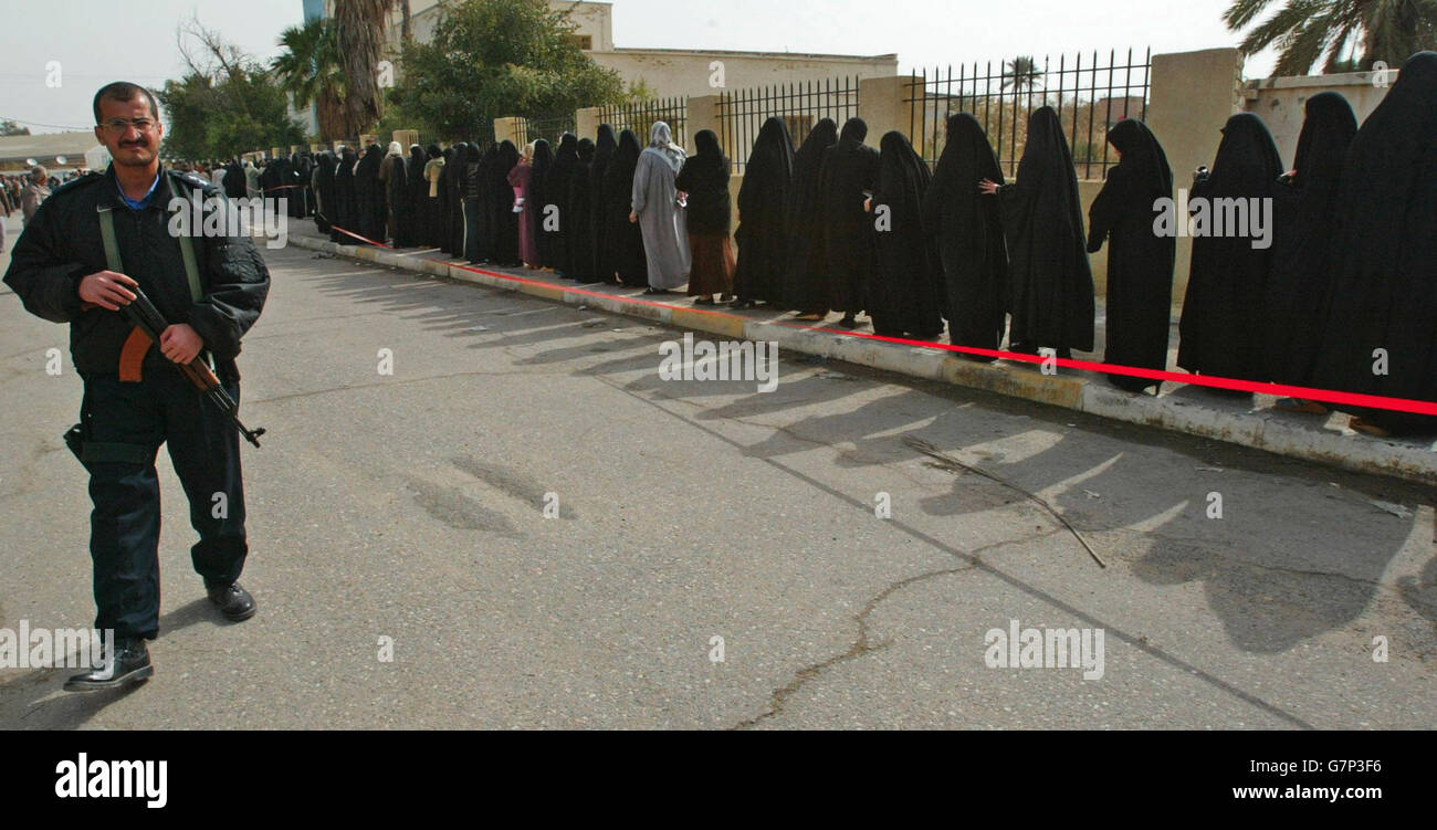 An Iraqi police officer guards as Iraqi women queue at a school polling ...