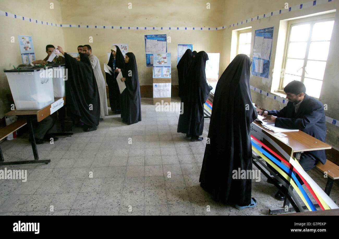 Election officials (R) check ID cards against the voters roll as an ...