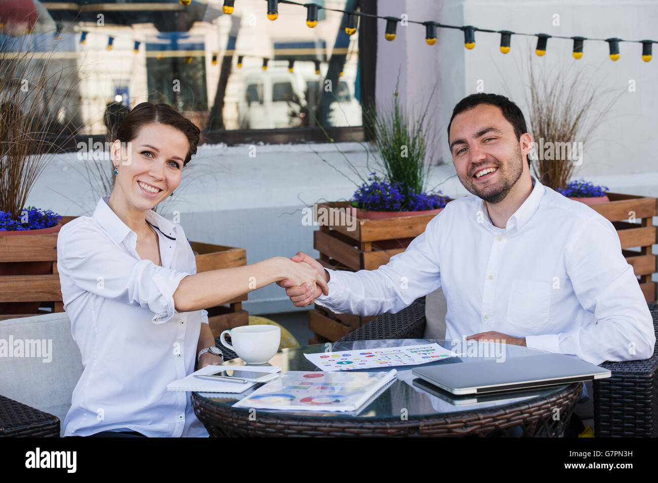 Young business people shake their hands in summer cafe Stock Photo - Alamy