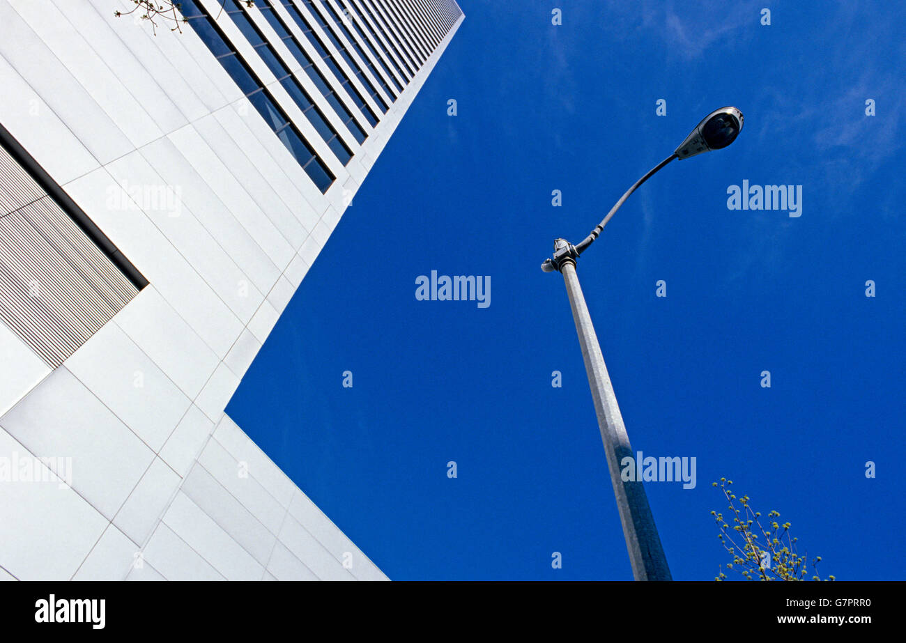 Looking up at lamp post and building with repeating lines and blue sky ...
