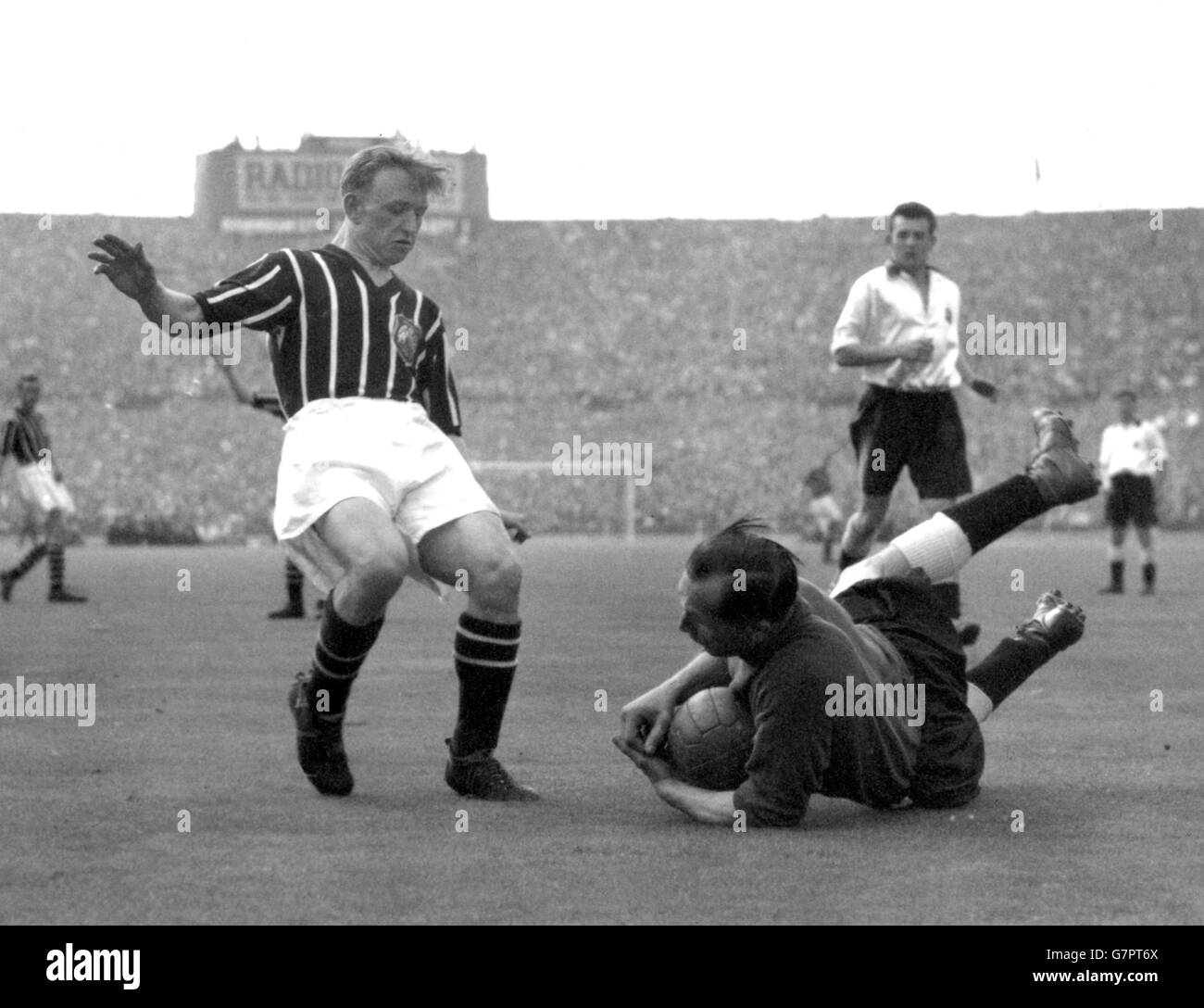 Birmingham's goalkeeper Gil Merrick dives to save the ball at the feet ...