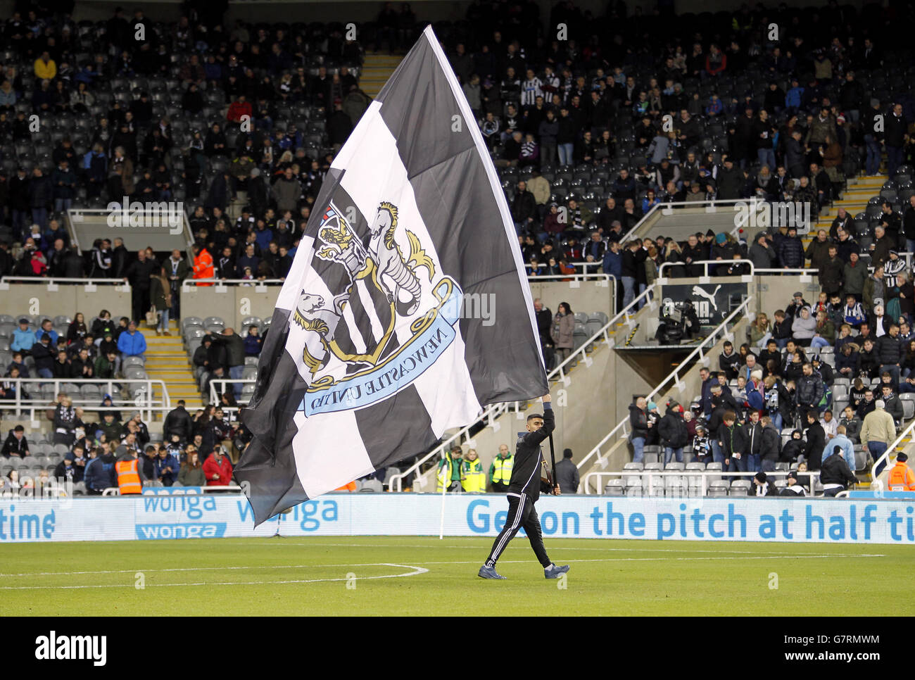 A giant Newcastle United flag is carried on the pitch before the game ...