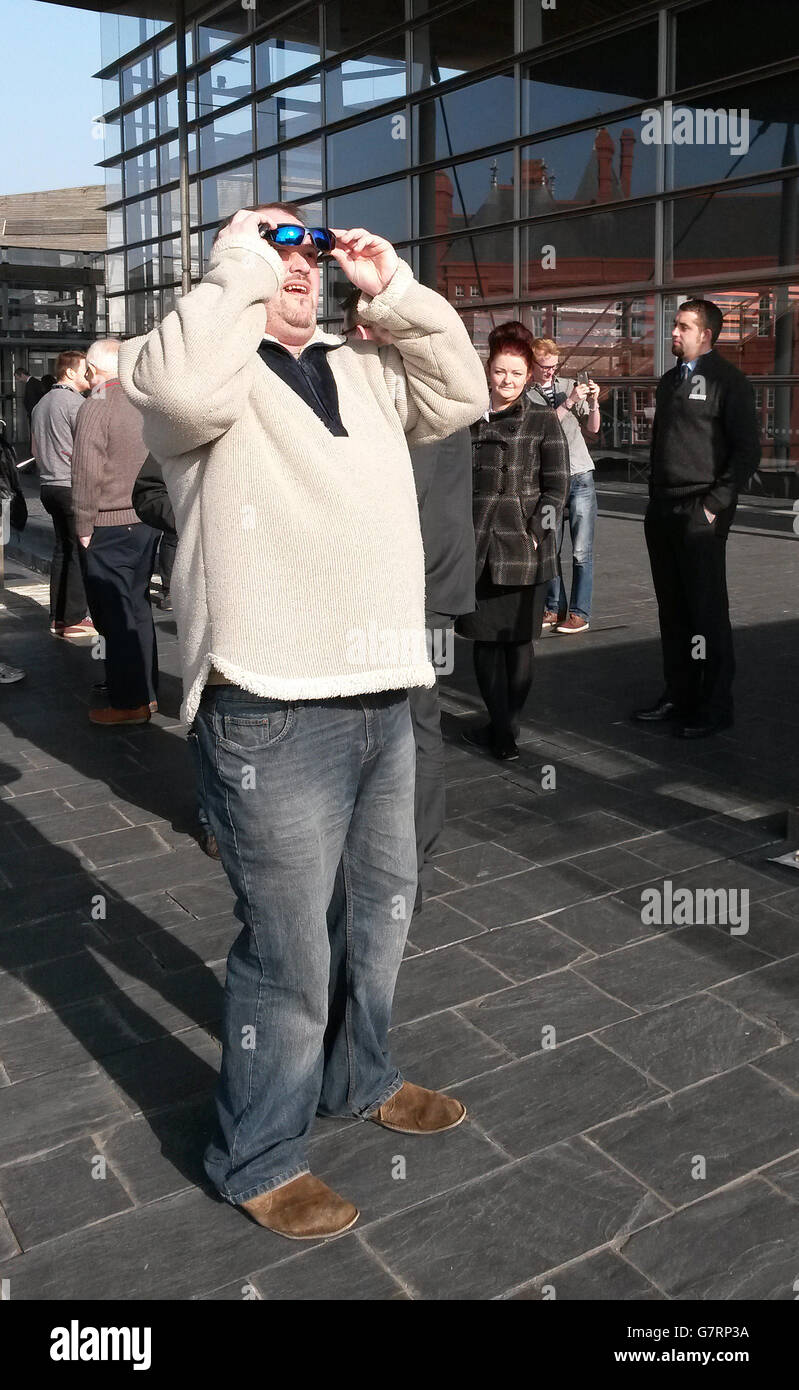 Members of the public look at the eclipse in Cardiff, Wales, as a near ...
