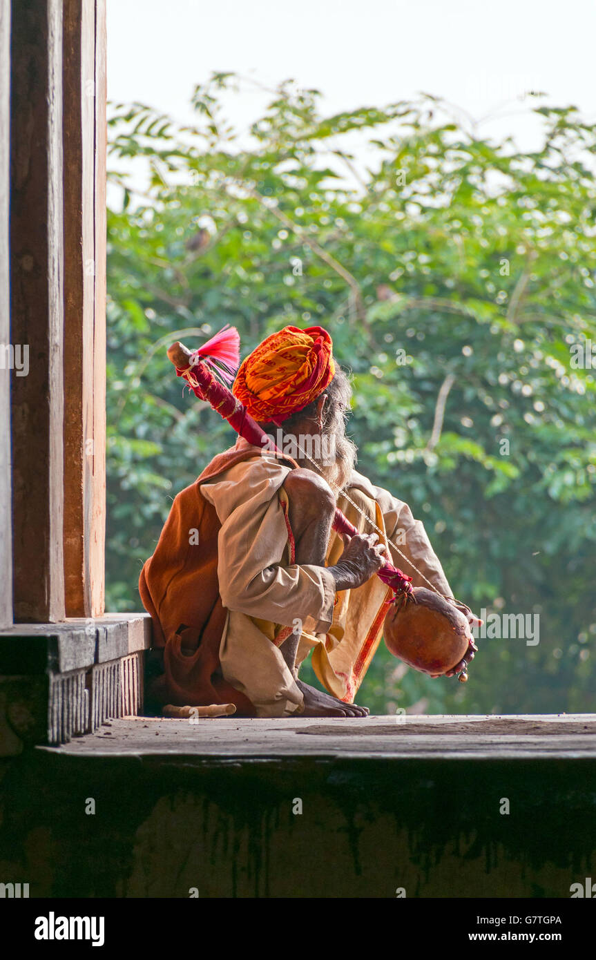 Unidentified Indian Sadhu sitting and playing the tumbi at window of ...