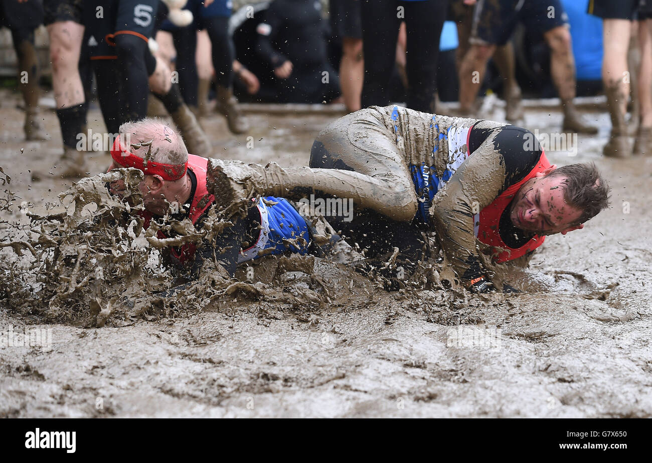 Participants slip and slide in the mud during Tough Mudder London West ...
