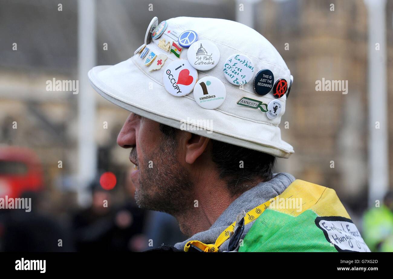 A man wears a hat covered with pin badges during a small protest ...