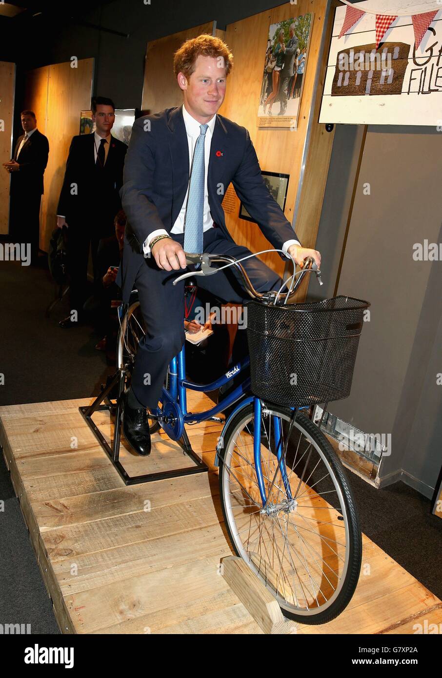 Prince Harry rides a bicycle which powers a television during a visit ...