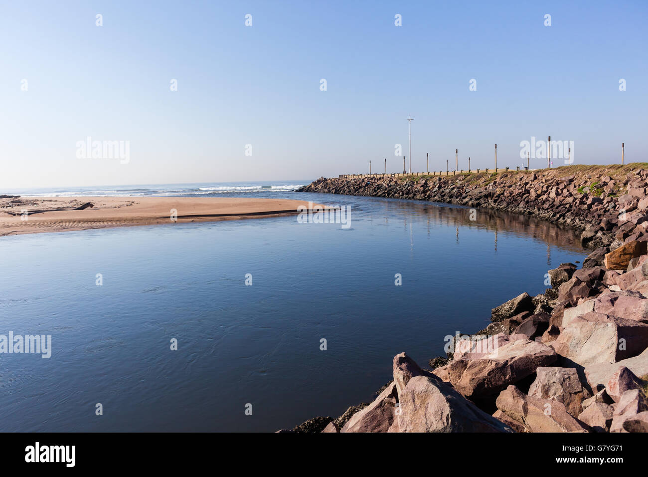 River mouth waters flowing towards blue ocean waves along rocky ...