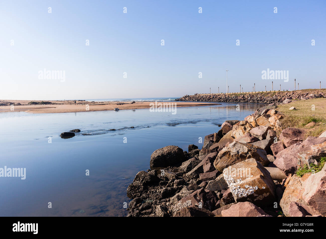 River mouth waters flowing towards blue ocean waves along rocky ...